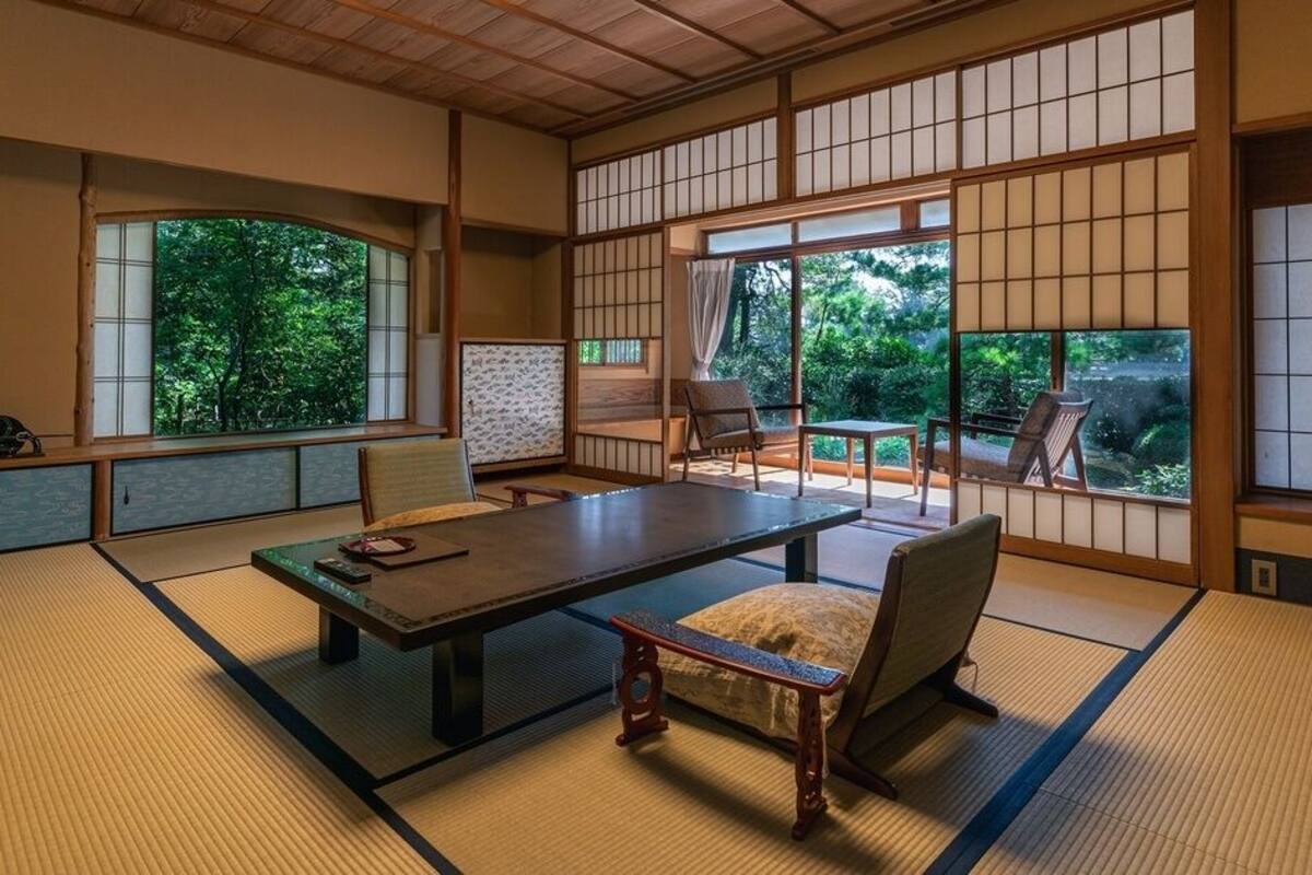 Um quarto japonês tradicional com tatames, uma mesa baixa e portas deslizantes.