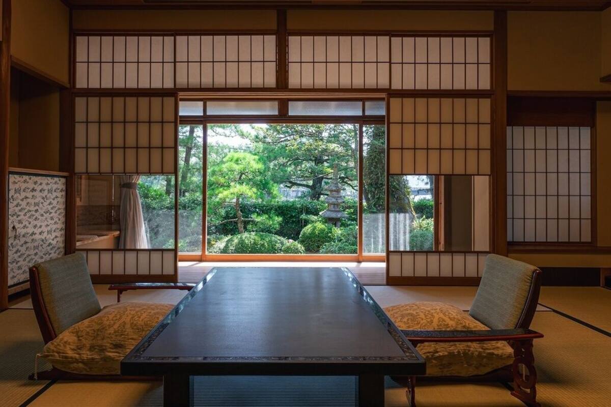 Um quarto japonês tradicional com tatames, uma mesa baixa e portas deslizantes.