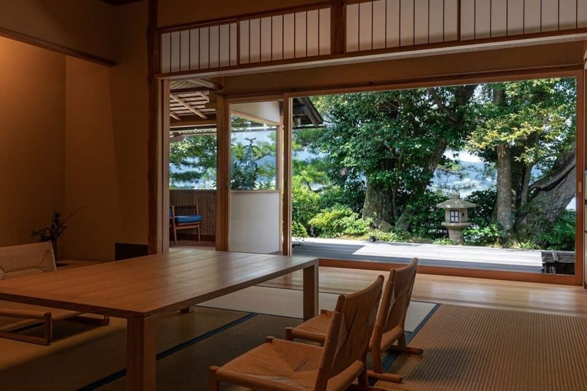 Um quarto japonês tradicional com tatames, uma mesa de madeira e cadeiras.