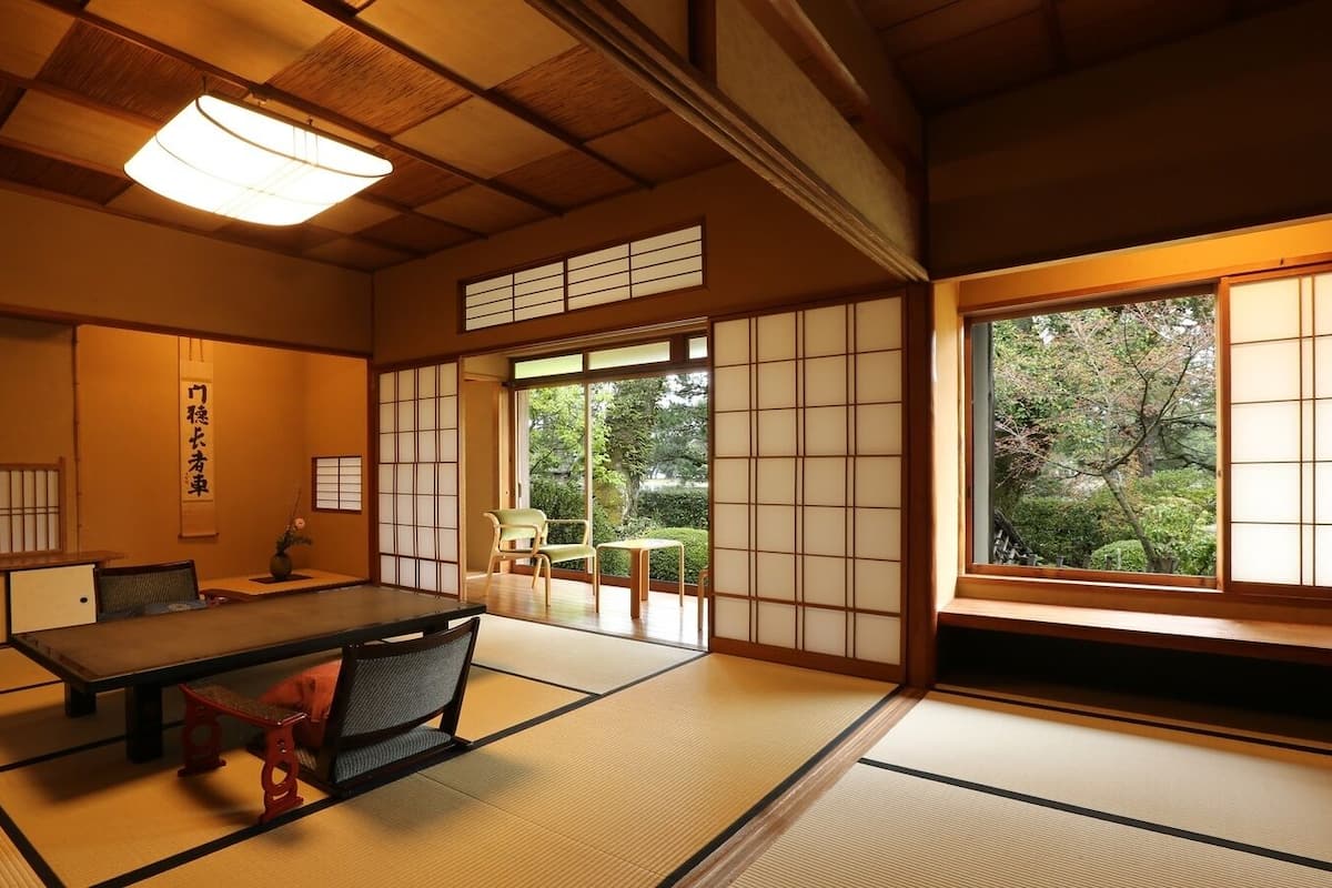 Um quarto japonês tradicional com tatames, uma mesa baixa e portas deslizantes.