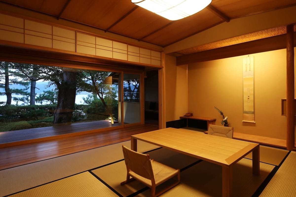 Um quarto japonês tradicional com tatames, uma mesa baixa e portas deslizantes.