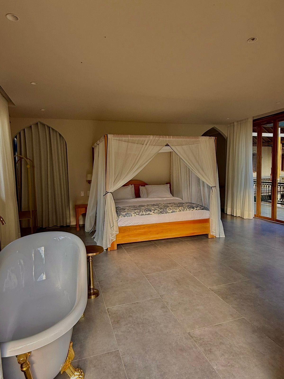 Quarto com cama de dossel, banheira e vista para o exterior.