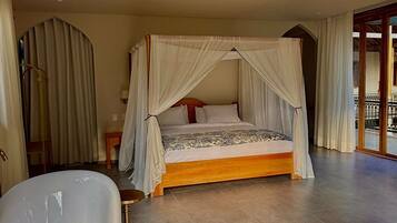 Quarto com cama de dossel, banheira e vista para o exterior.