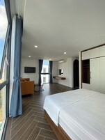 Quarto de hotel moderno com uma cama grande, um sofá, uma escrivaninha e vista para a cidade.