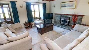 Uma sala de estar com lareira, sofás, uma mesa de centro e televisão.