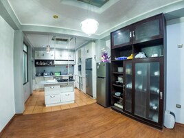 Cozinha com armários brancos, forno embutido, geladeira e piso de madeira.