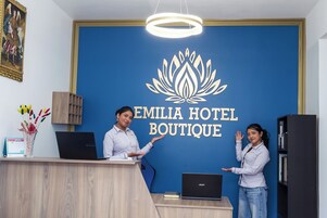 Balcão de recepção com parede azul, um logotipo e dois funcionários.