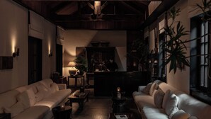 Uma sala de estar acolhedora com um sofá, mesa de centro e uma pessoa trabalhando em uma escrivaninha.