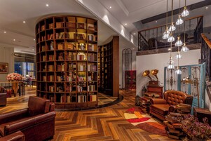 Uma biblioteca espaçosa com uma grande estante de madeira, assentos de couro e padrão de piso em herringbone.