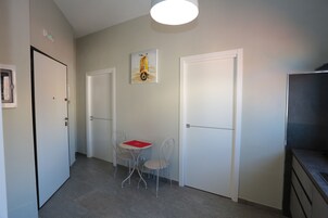 Um corredor com duas portas, uma mesa de jantar com cadeiras e um quadro na parede.
