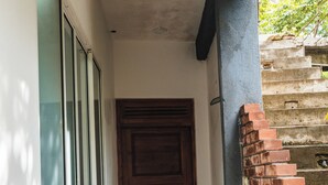 Um corredor estreito com uma porta de madeira, uma janela e uma parede de tijolos.