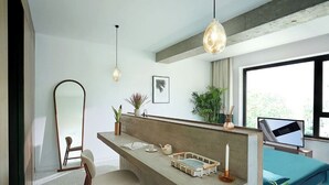 Um espaço de estar moderno com uma ilha de concreto, um espelho grande, um sofá, uma TV e uma planta.