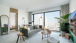 Uma sala de estar moderna com um sofá, mesa de centro e uma grande janela com vista para a cidade.