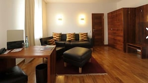 Uma sala de estar moderna com sofá, banquinho, piso de madeira e um espaço de refeições com mesa e cadeiras.