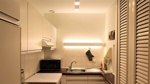 Uma cozinha compacta com micro-ondas, pia e armários.