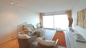 Uma sala de estar moderna com um sofá, poltronas, uma mesa de centro e uma estante.