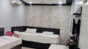 Quarto com duas camas, uma cadeira rosa e cortina estampada.