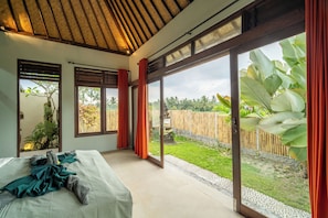 Quarto com cama, janelas amplas e vista para um jardim.