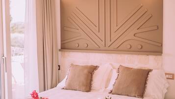 Quarto com uma cama grande, cabeceira decorativa, mesa de cabeceira e vista para o exterior.