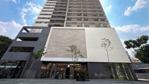 Um edifício de vários andares com design arquitetônico moderno, com varandas e grandes janelas.