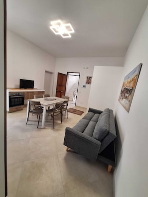 Uma sala de estar moderna com sofá, mesa de jantar e área de cozinha.