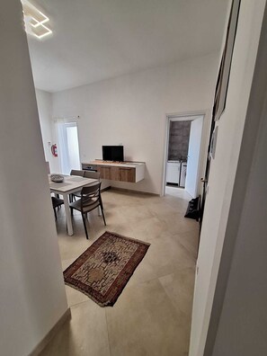 Um apartamento moderno com sala de jantar, cozinha com televisão e área de estar.