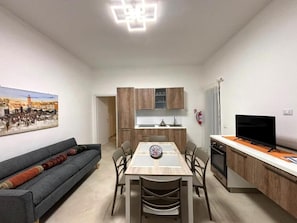 Um espaço compacto com mesa de jantar, sofá, kitchenette e televisão.