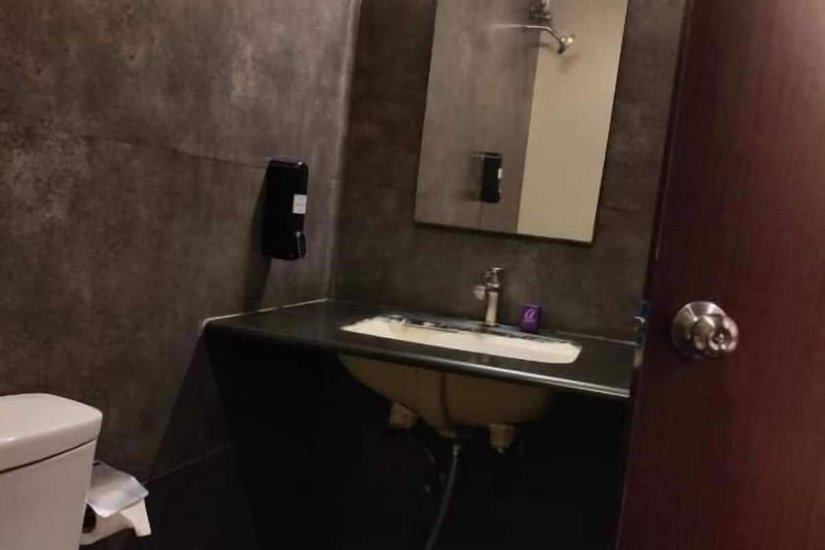 Casa de banho com sanita, lavatório, espelho e porta.