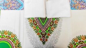Uma toalha branca dobrada sobre um tecido estampado.