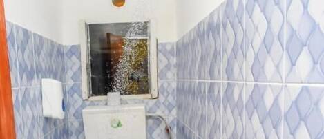 Uma casa de banho pequena com chuveiro, sanita e lavatório.