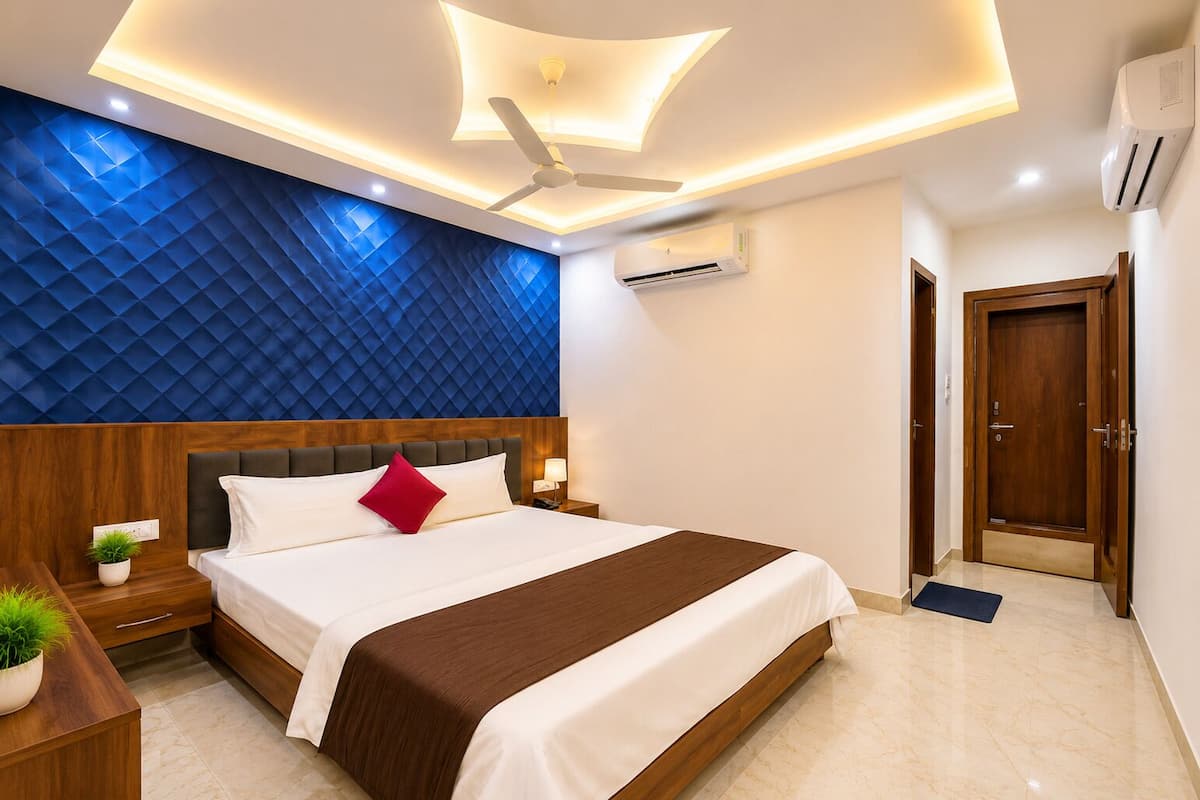 Quarto de hotel moderno com uma cama, mesas de cabeceira, um ventilador de teto e um aparelho de ar condicionado.