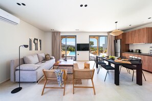 Uma sala de estar moderna com sofá, mesa de centro e área de jantar com cadeiras.