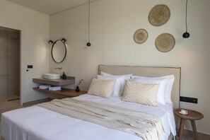 Quarto moderno com cama, mesa de cabeceira e toucador fixado na parede com lavatório.