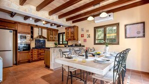 Cozinha com armários de madeira, uma ilha central e uma área de jantar com mesa e cadeiras.