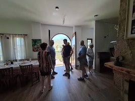 Quarto com uma mesa de jantar, cadeiras, um quadro e vista através de uma porta aberta.