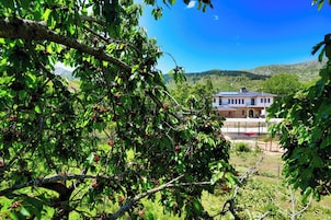 Uma casa com jardim, rodeada por colinas.