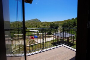 Uma varanda com vista para uma paisagem verde, um pequeno pavilhão e uma bandeira.