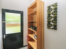 Um quarto com uma porta preta, uma estante de madeira e uma parede com padrão geométrico.
