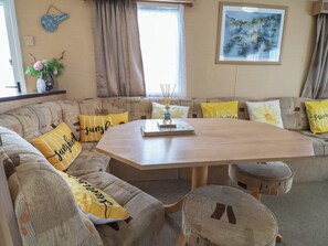 Uma sala de estar aconchegante com uma mesa de madeira redonda, sofás estampados e almofadas decorativas.