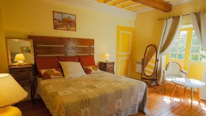 Um quarto com cama de madeira, abajures, uma cadeira e uma janela com cortinas.