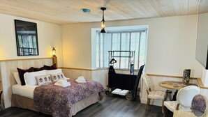 Um quarto com uma cama, escrivaninha, cadeira, radiador e janela com persianas.