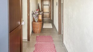 Um corredor com portas de madeira, uma cesta de vime com flores e um tapete estampado.