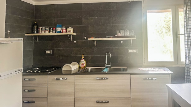Uma cozinha moderna com azulejos escuros, eletrodomésticos de aço inoxidável e armários de madeira.
