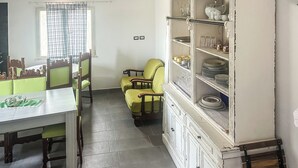 Uma área de refeições com mesa, cadeiras e um armário com louças.