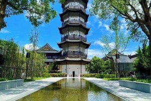 Um pagode tradicional de vários níveis com um espelho de água à frente, rodeado por vegetação.