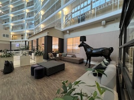 Amplo espaço interno com teto alto, móveis modernos e uma grande escultura.