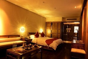 Quarto de hotel com cama, mesas de cabeceira, um sofá e uma escrivaninha com abajur.
