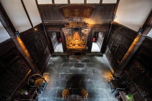 Interior de madeira tradicional com altar central, soalho de pedra e duas cadeiras.
