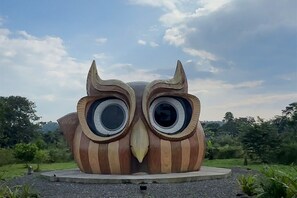 Uma grande escultura de madeira de uma coruja, com olhos e base circulares.