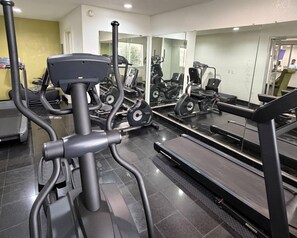 Uma academia com equipamentos de ginástica, incluindo esteiras e elípticos.